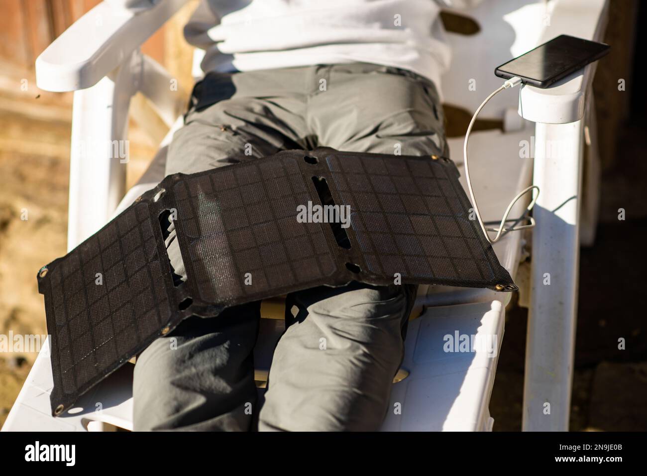 Portable solar battery. Lying on the legs of a resting unrecognizable ...