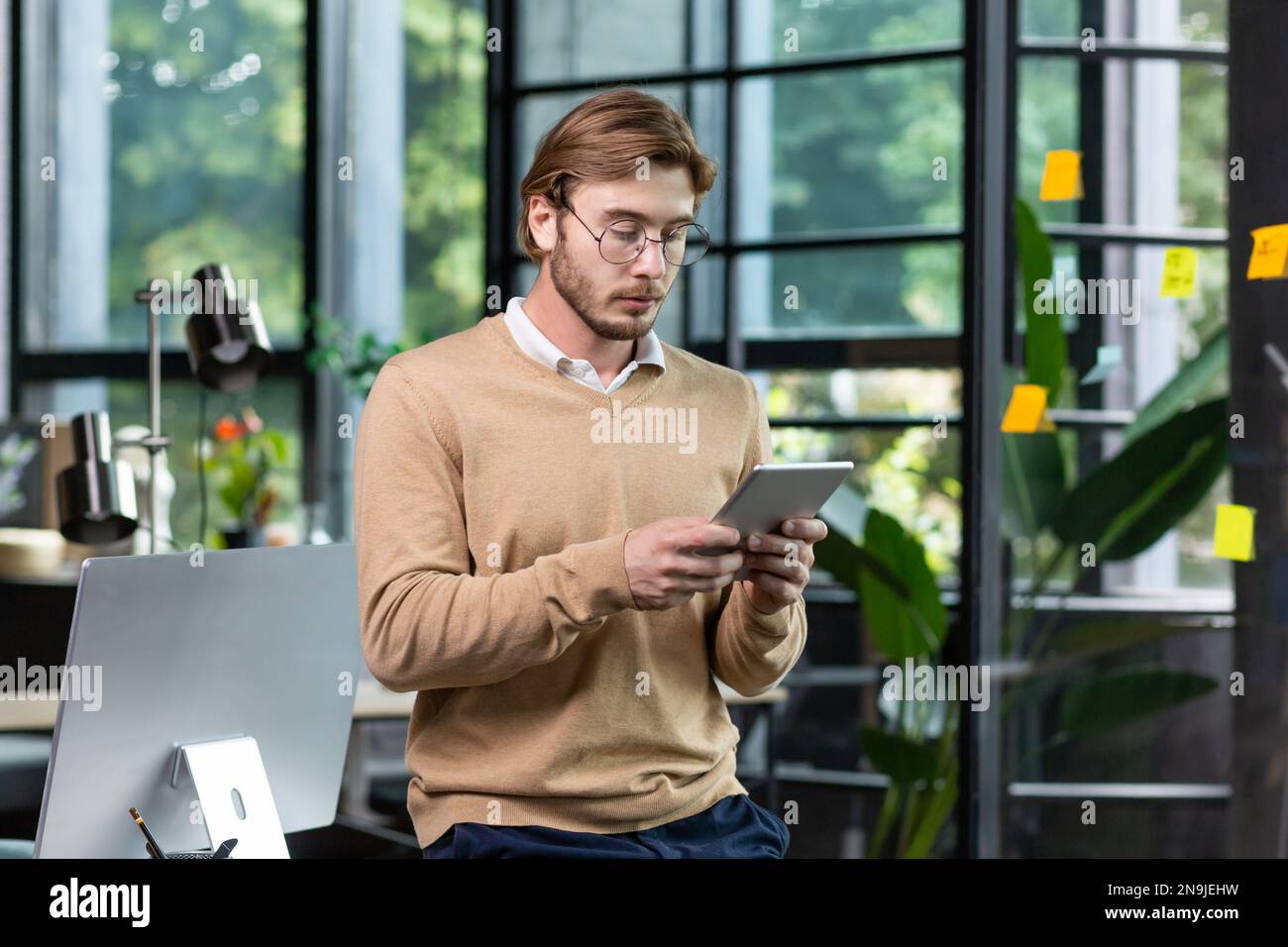 Portrait of a young male programmer who is standing in the office at ...