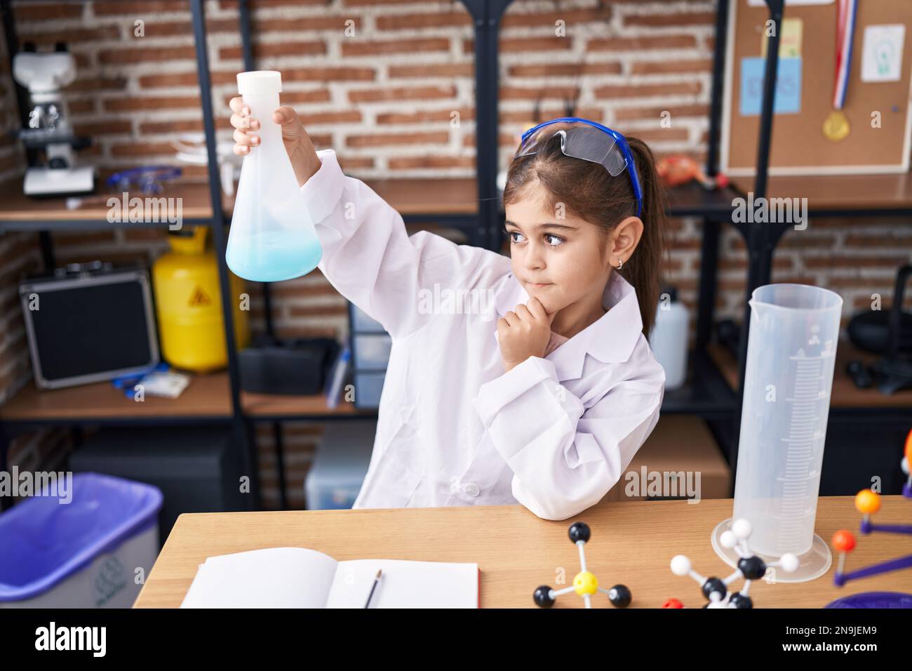 Adorable hispanic girl student holding test tube at laboratory ...