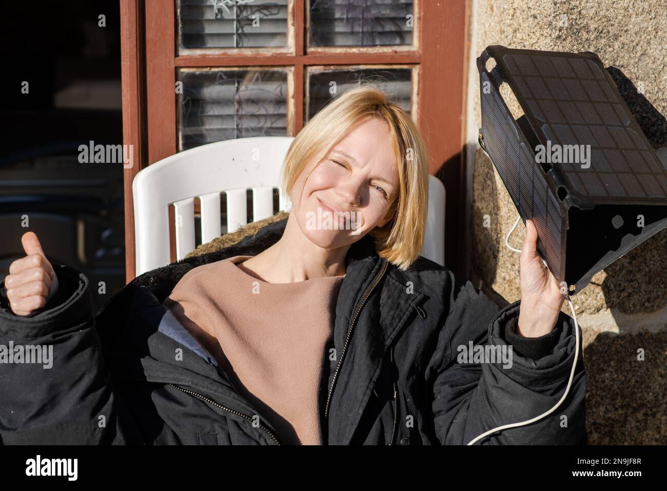 Portable solar battery in the hands of a woman. Charging mobile gadgets ...