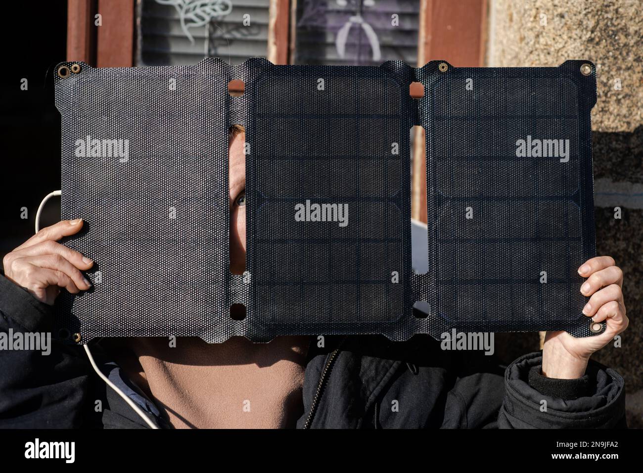 Portable solar battery in the hands of a woman. Charging mobile gadgets ...