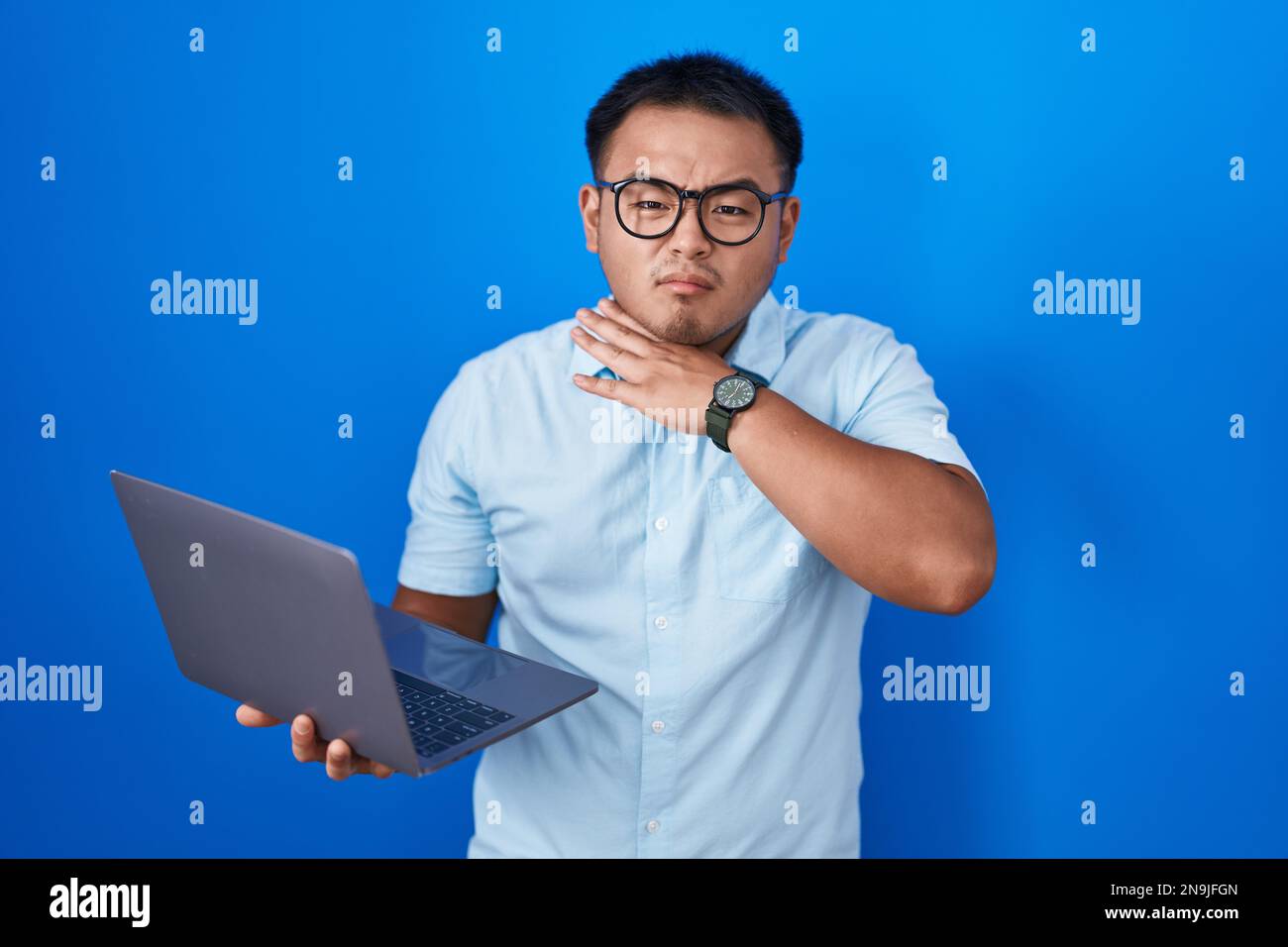 Chinese young man using computer laptop cutting throat with hand as ...