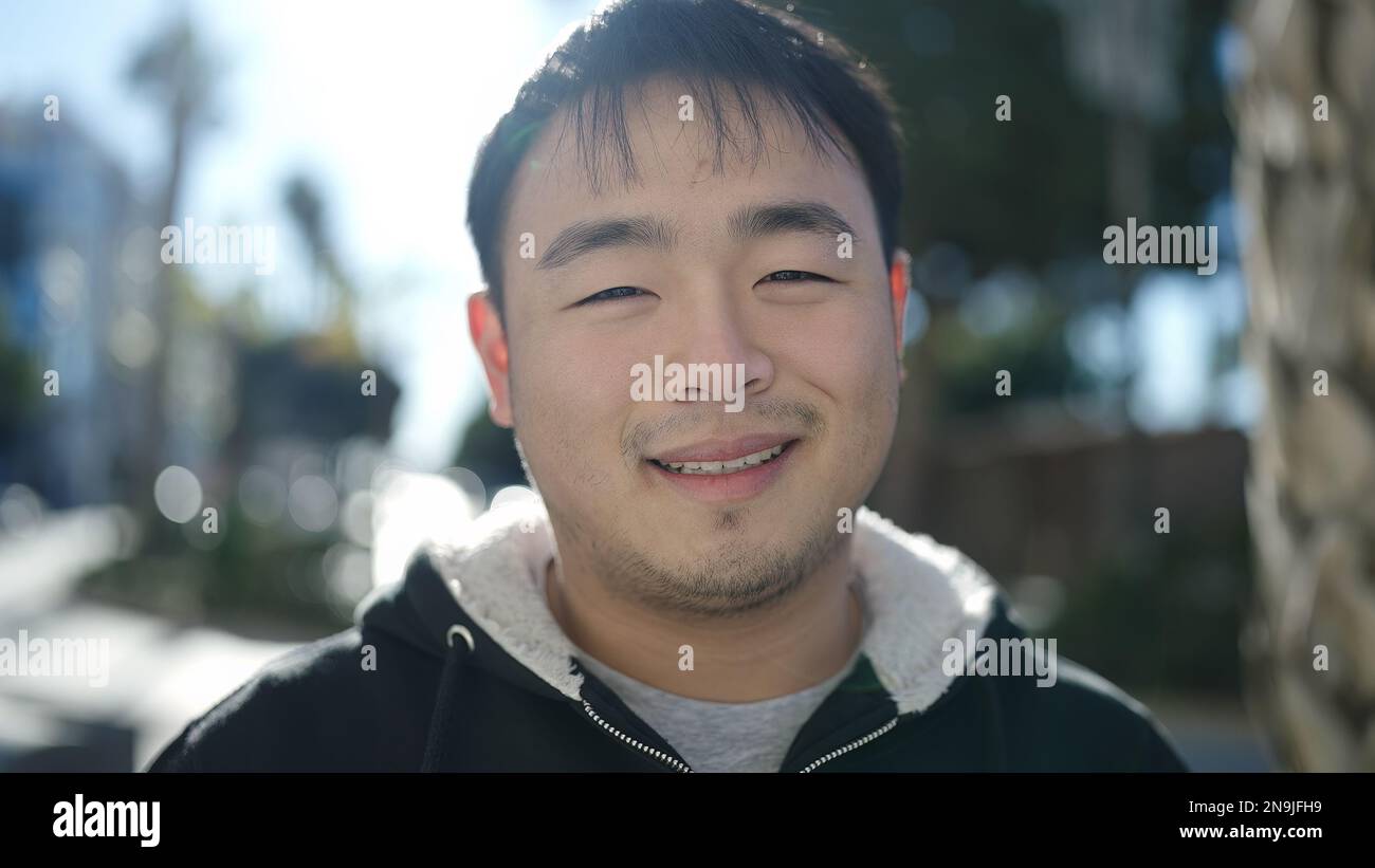 Young chinese man smiling confident standing at street Stock Photo - Alamy