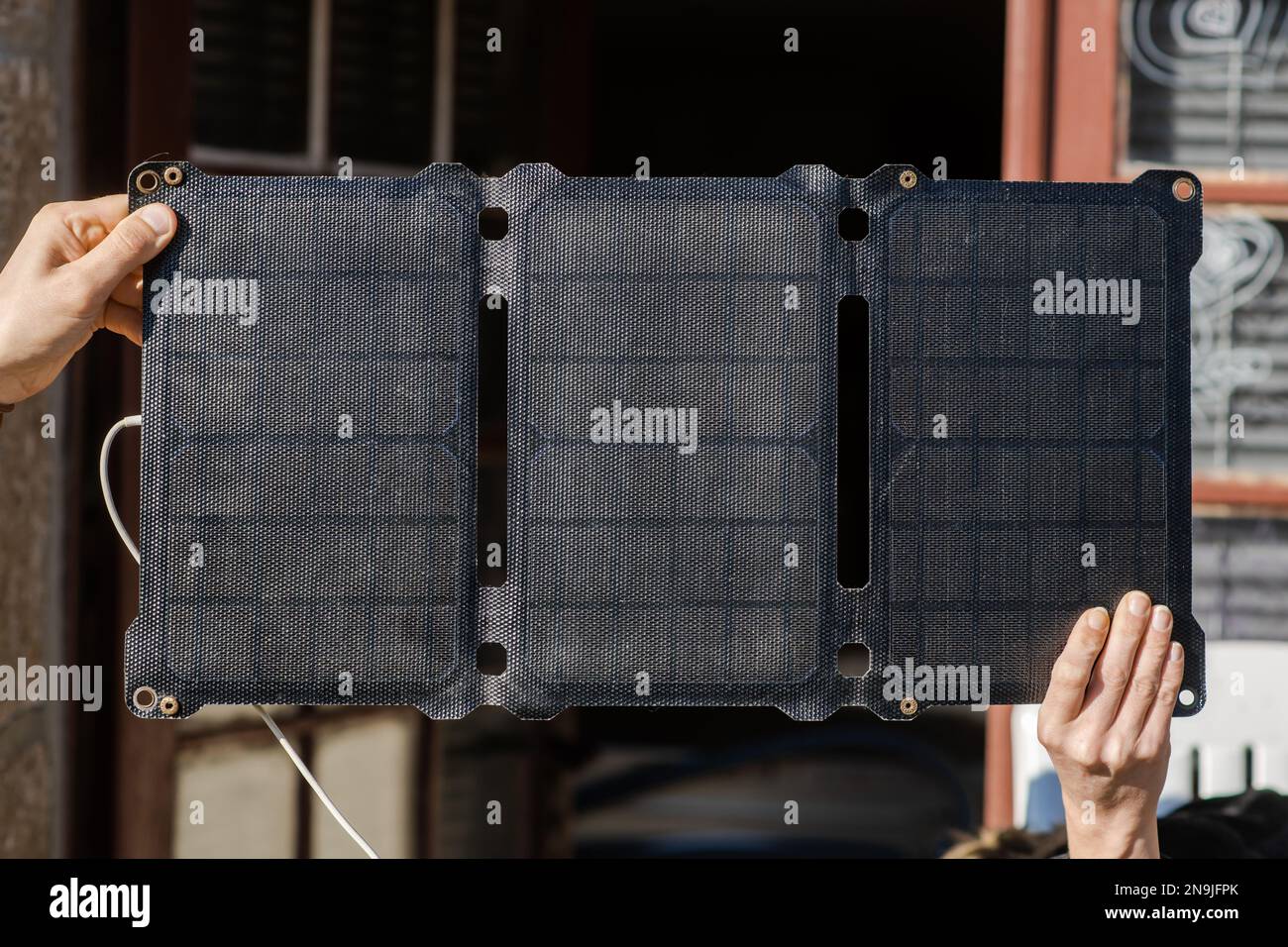 Portable solar battery in male and female hand. Charging mobile gadgets ...