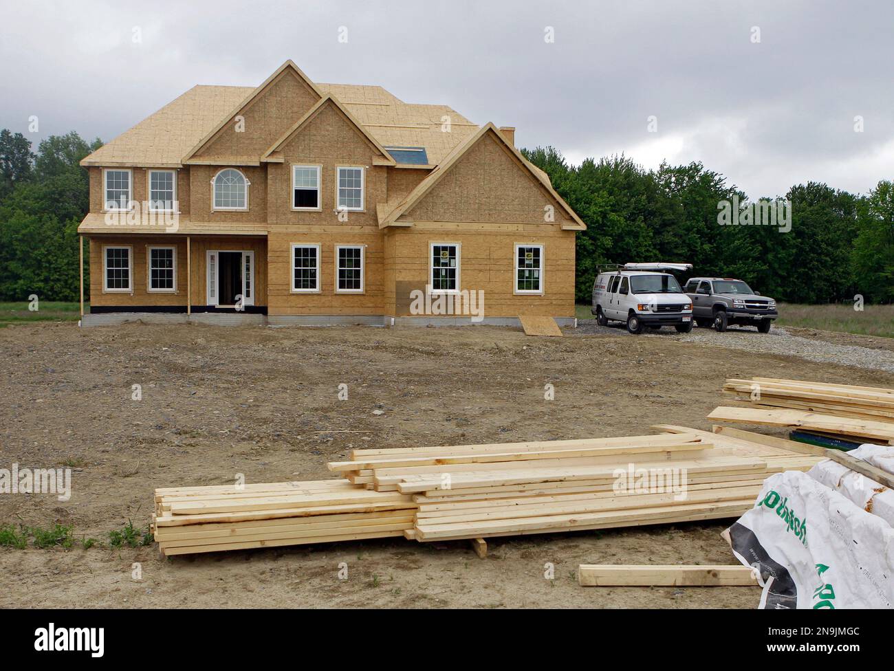 Building materials lay stacked in front of a new home under ...