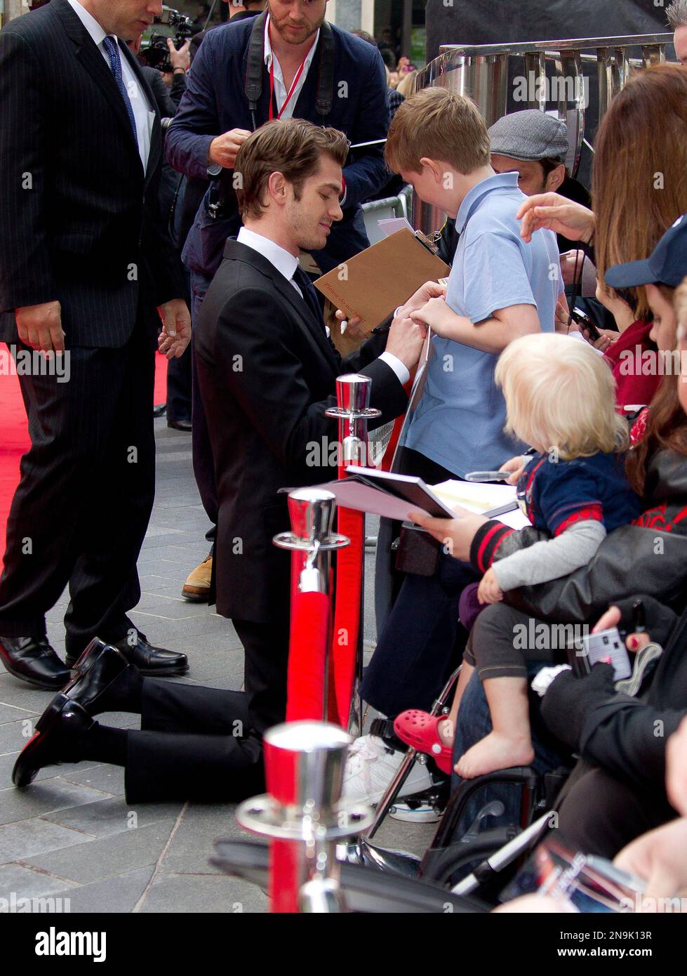 British actor Andrew Garfield kneels down on the red carpet to sign ...