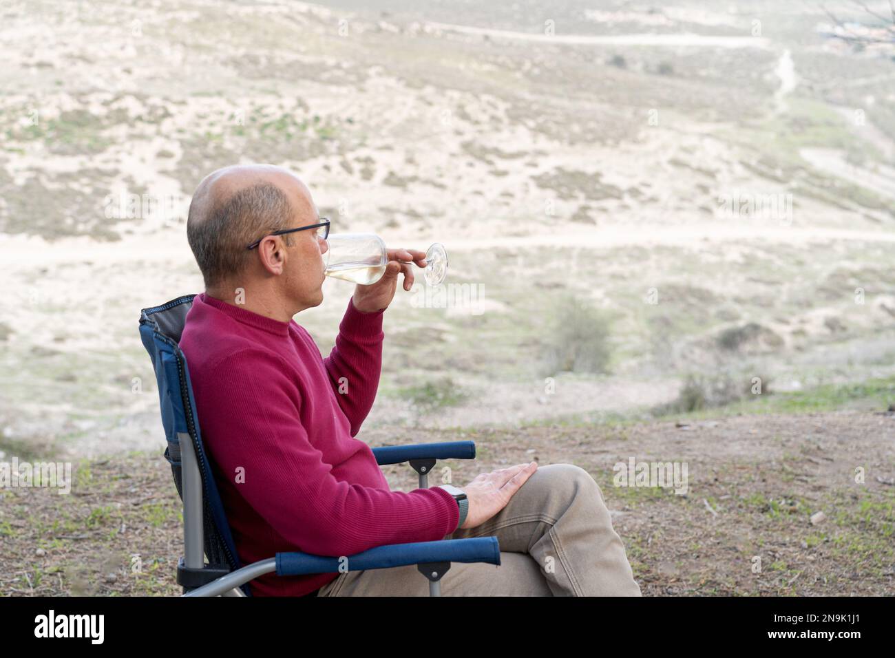 Man sitting on folding chair, drinking wine, relaxing and looking ...