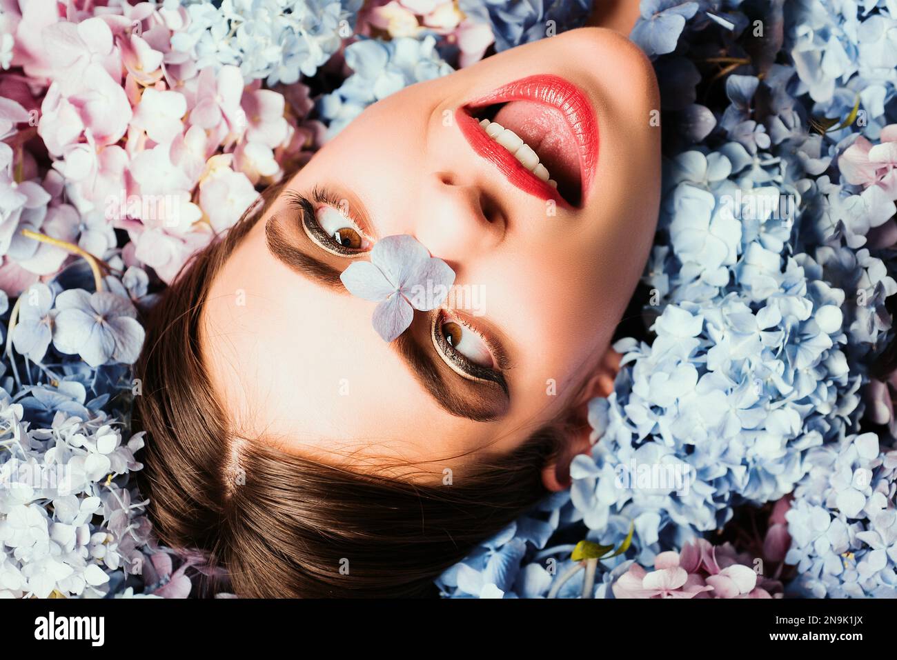 Nature beauty. Funny Woman lying on flowers. Unity with nature. Blossom ...