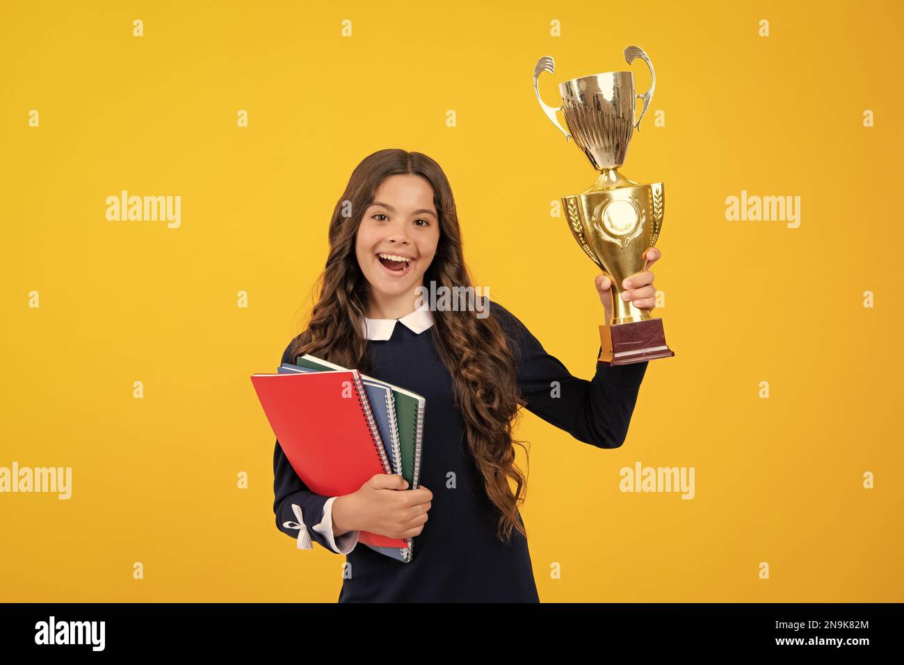 Schoolgirl in school uniform celebrating victory with trophy. Teen ...