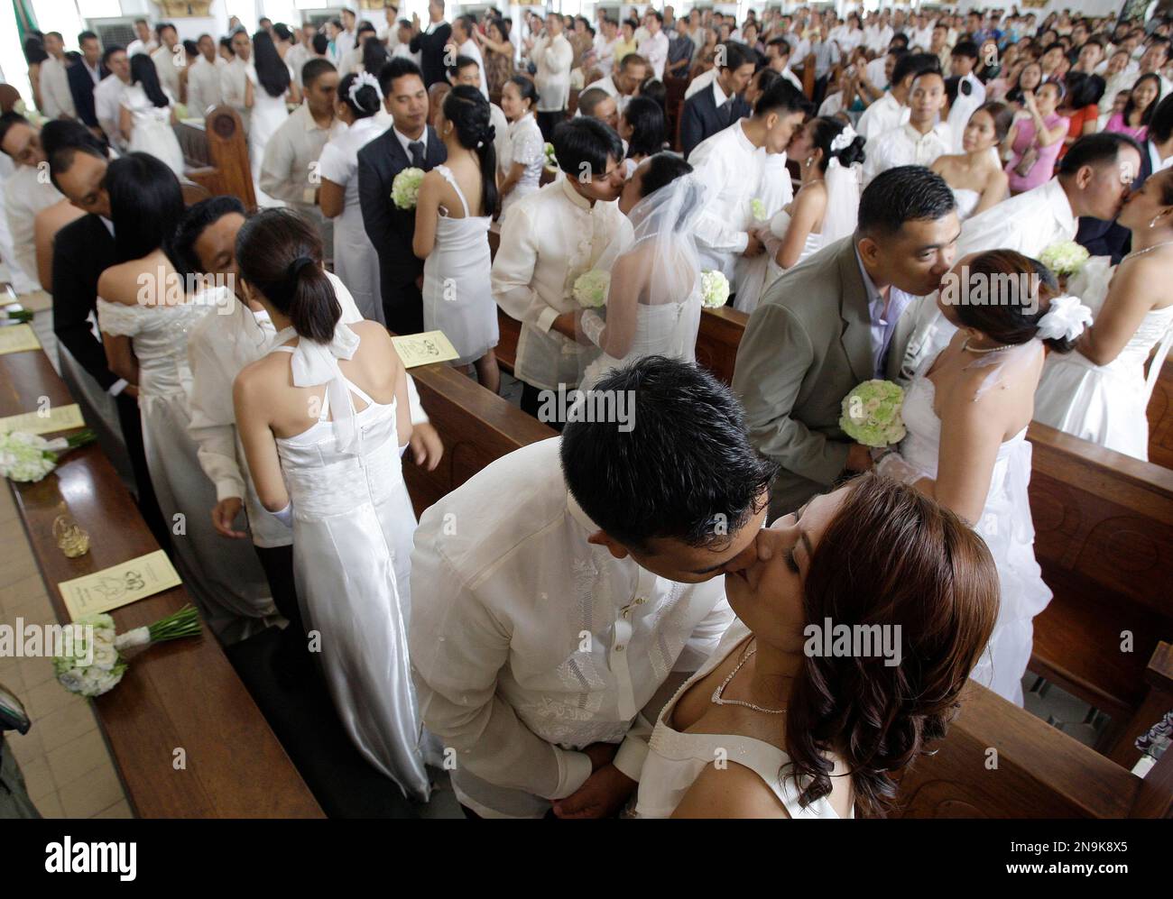Filipino couples kiss during a mass wedding ceremony inside a chapel in ...