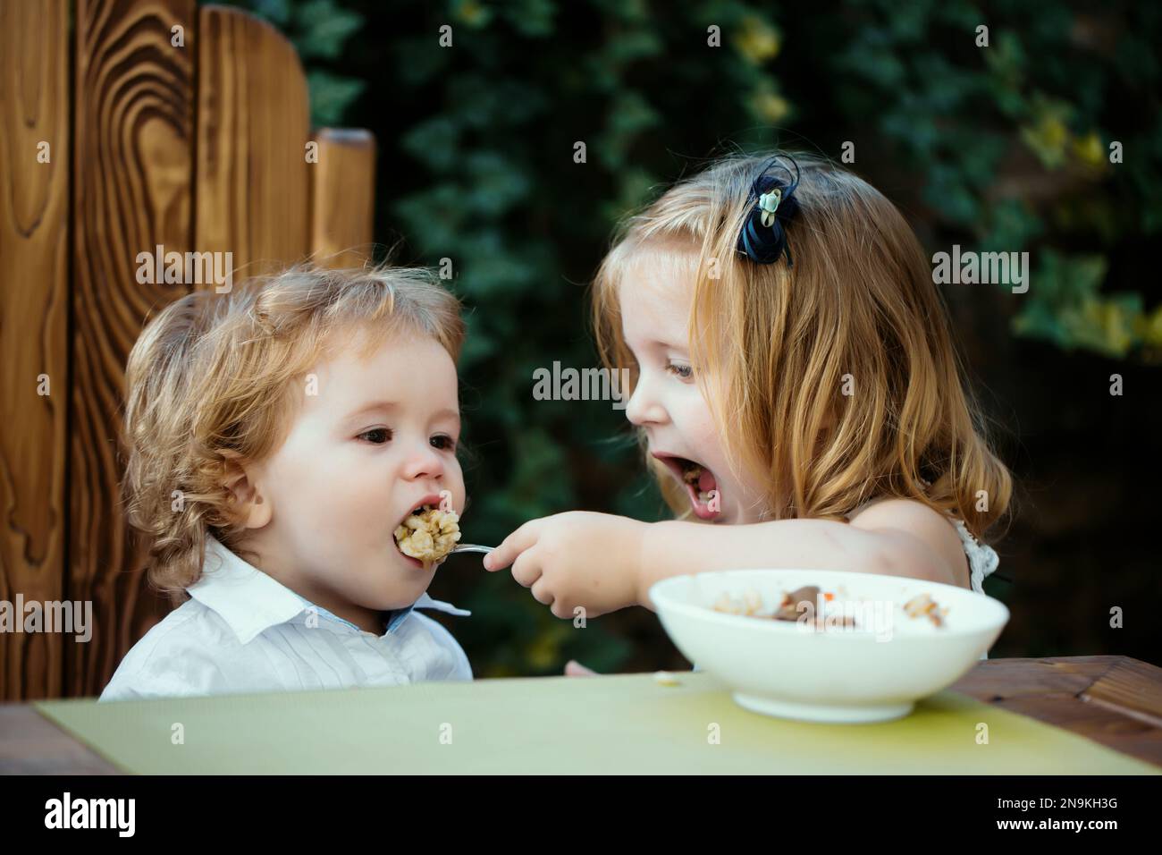 Sister feeding baby boy. Girl feeds brother with a spoon. Kid food ...