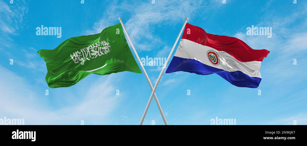 two crossed flags Paraguay and Saudi Arabia waving in wind at cloudy ...