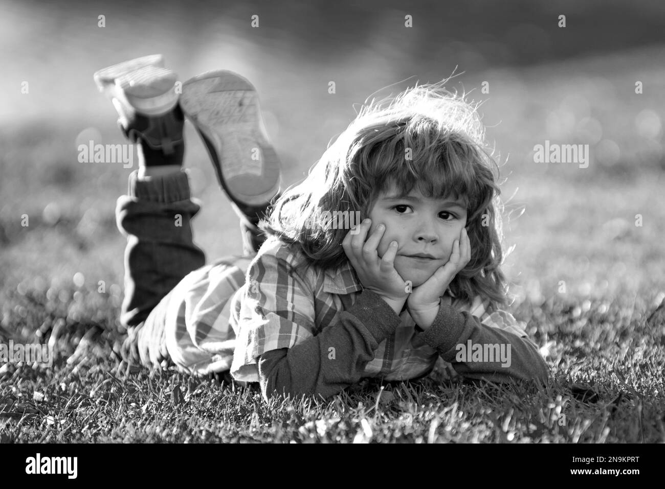 Child in park outdoor. Spring kid lying on grass. Summer boy walk ...