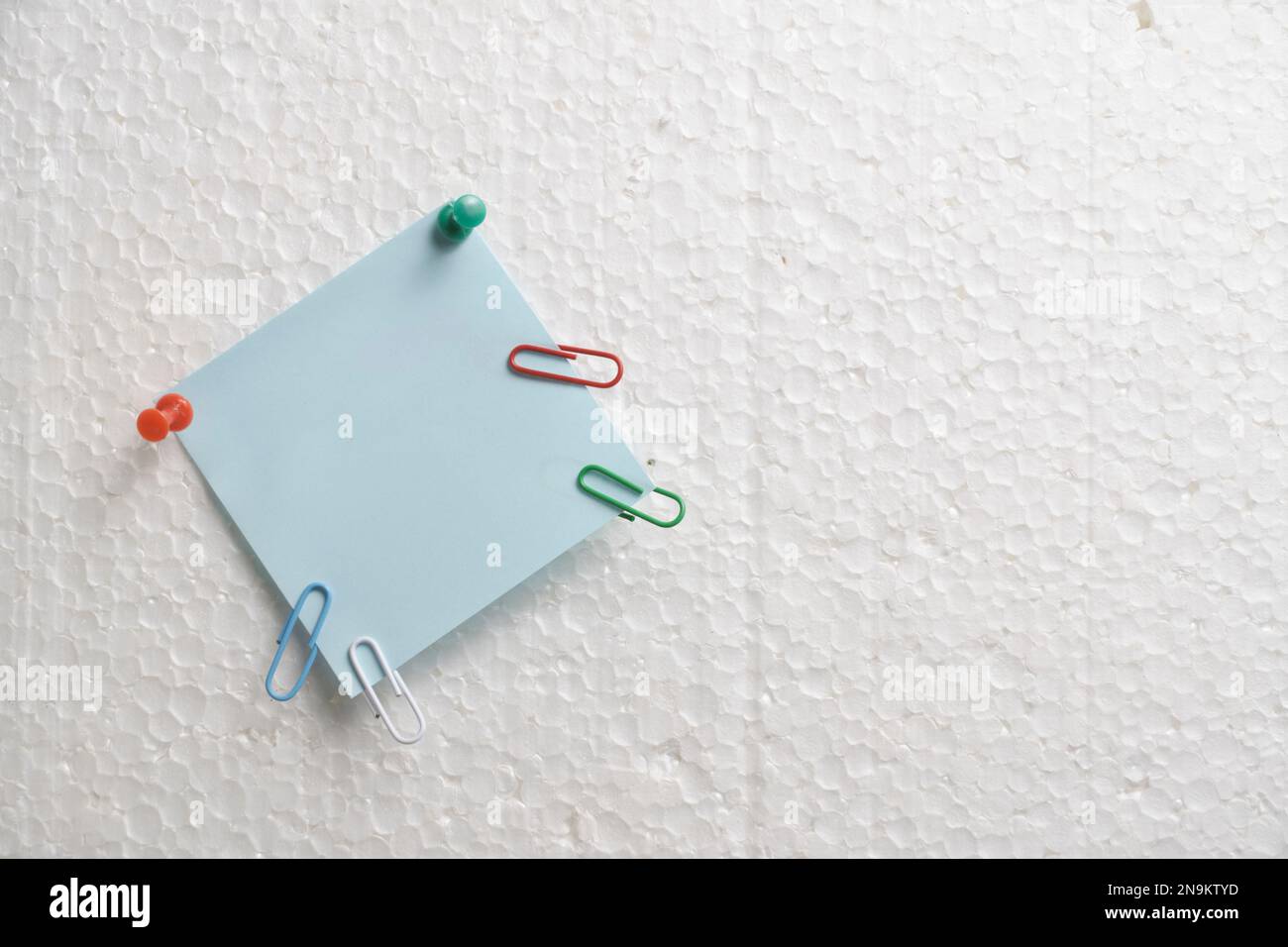 Hanging from wall with help stationery buttons is blue sticker for ...