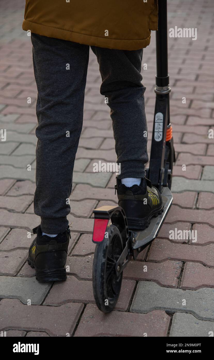Teenager rides a scooter on a brick road Stock Photo - Alamy