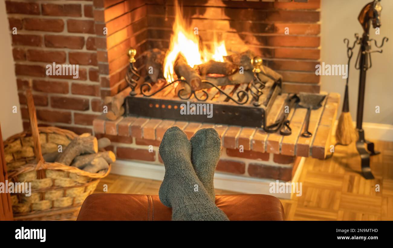 Feet with socks in front of the wood fireplace fire to warm them in ...