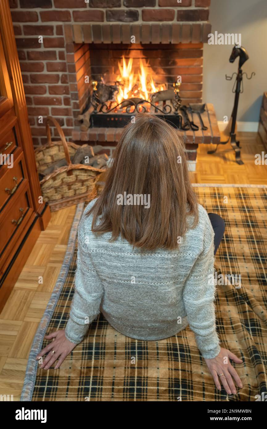 Woman sitting on top of a blanket on the floor and facing the cozy ...
