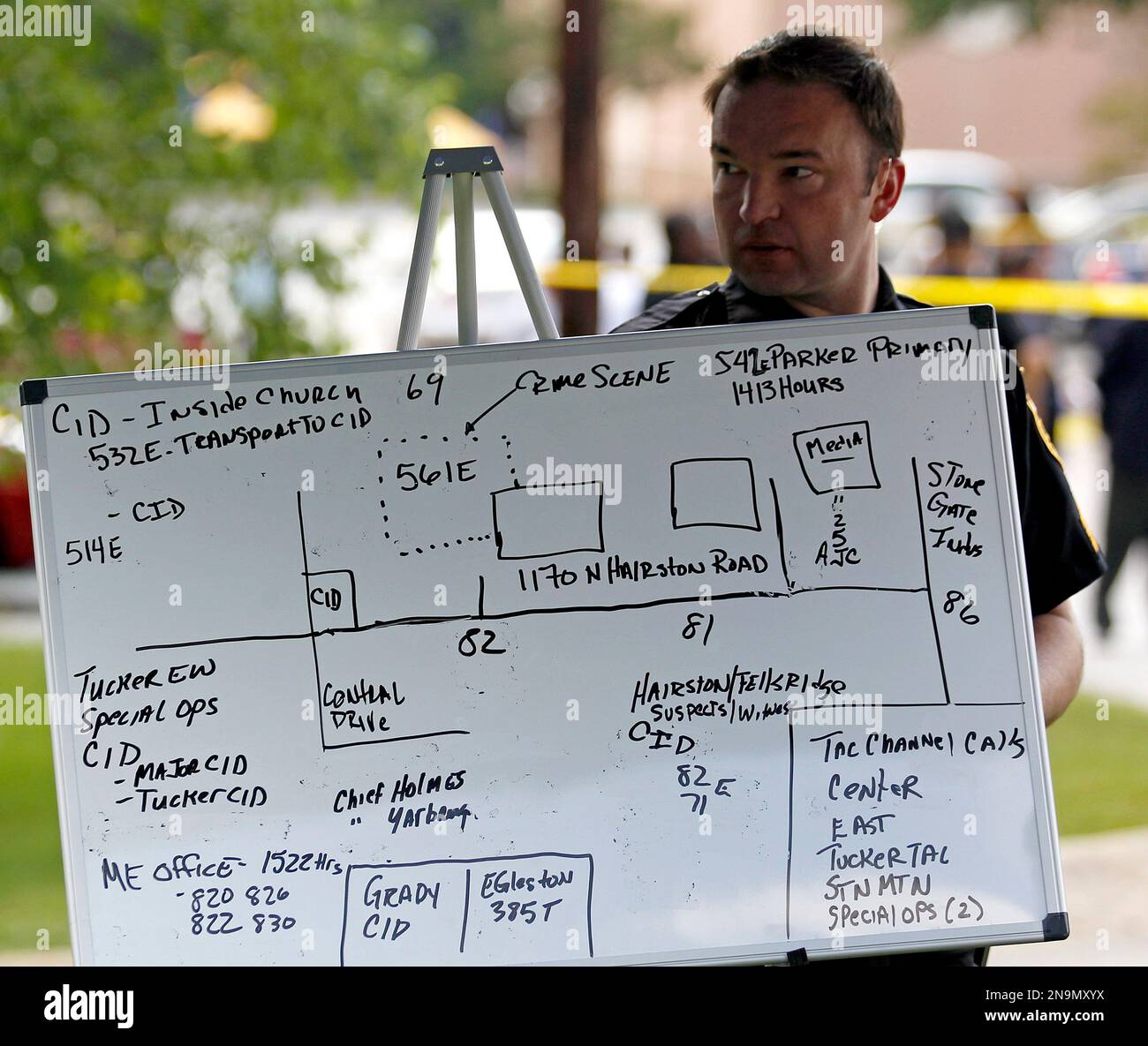 A police officer holds up a billboard showing the layout of the crime ...
