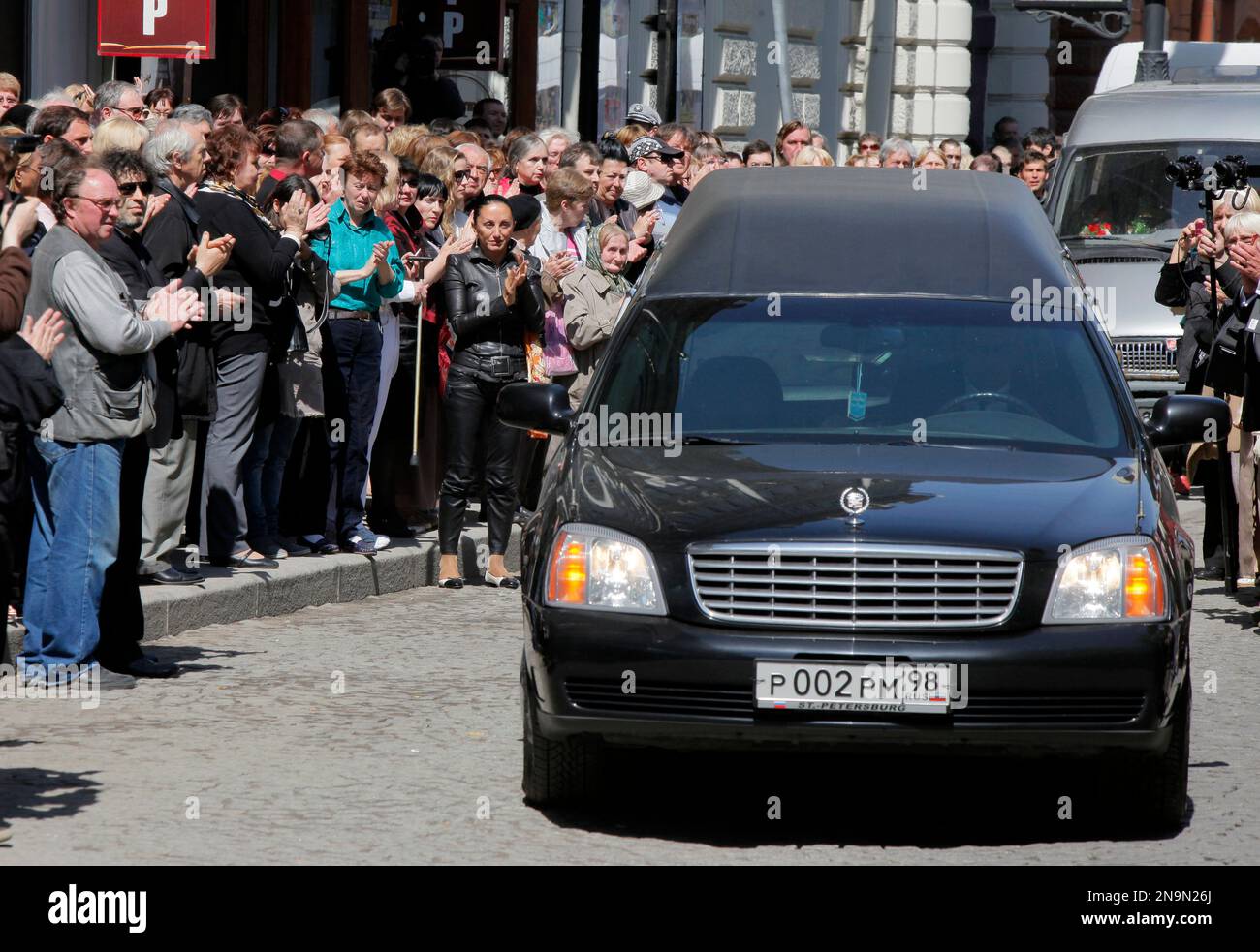 People applaud a hearse carrying the coffin of Russian singer Eduard ...