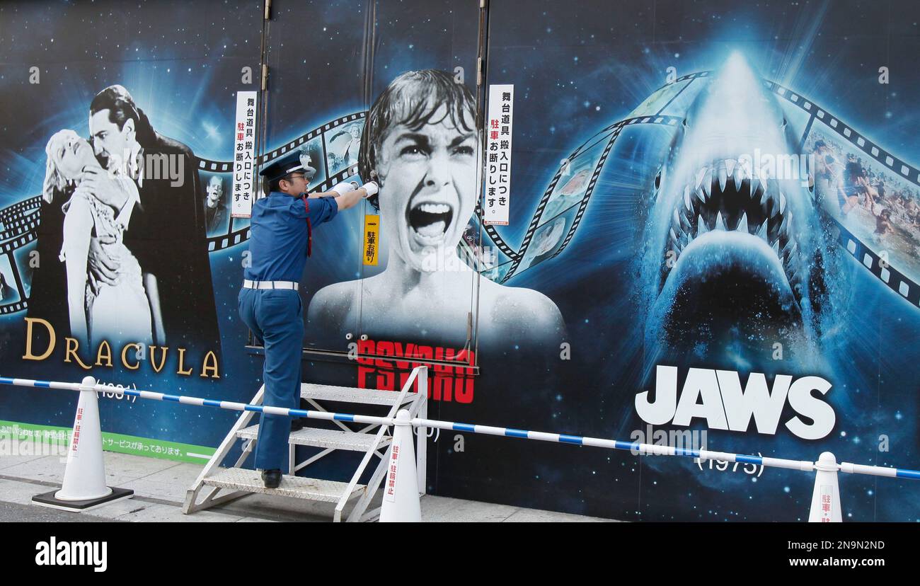 A security guard checks a stage door of a theater painted with posters ...
