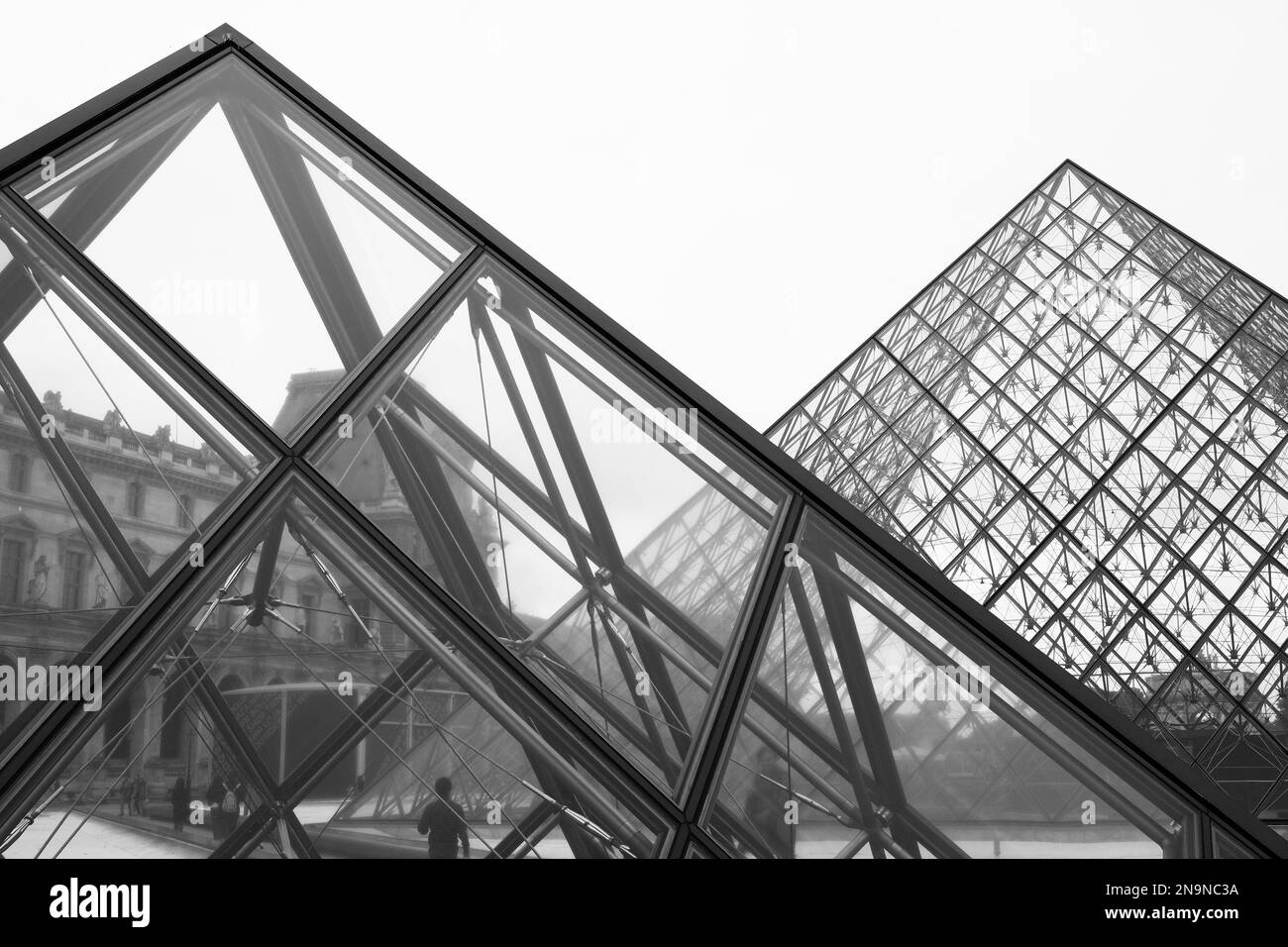 A grayscale shot of the exterior of the Louvre Pyramid in Paris, France ...