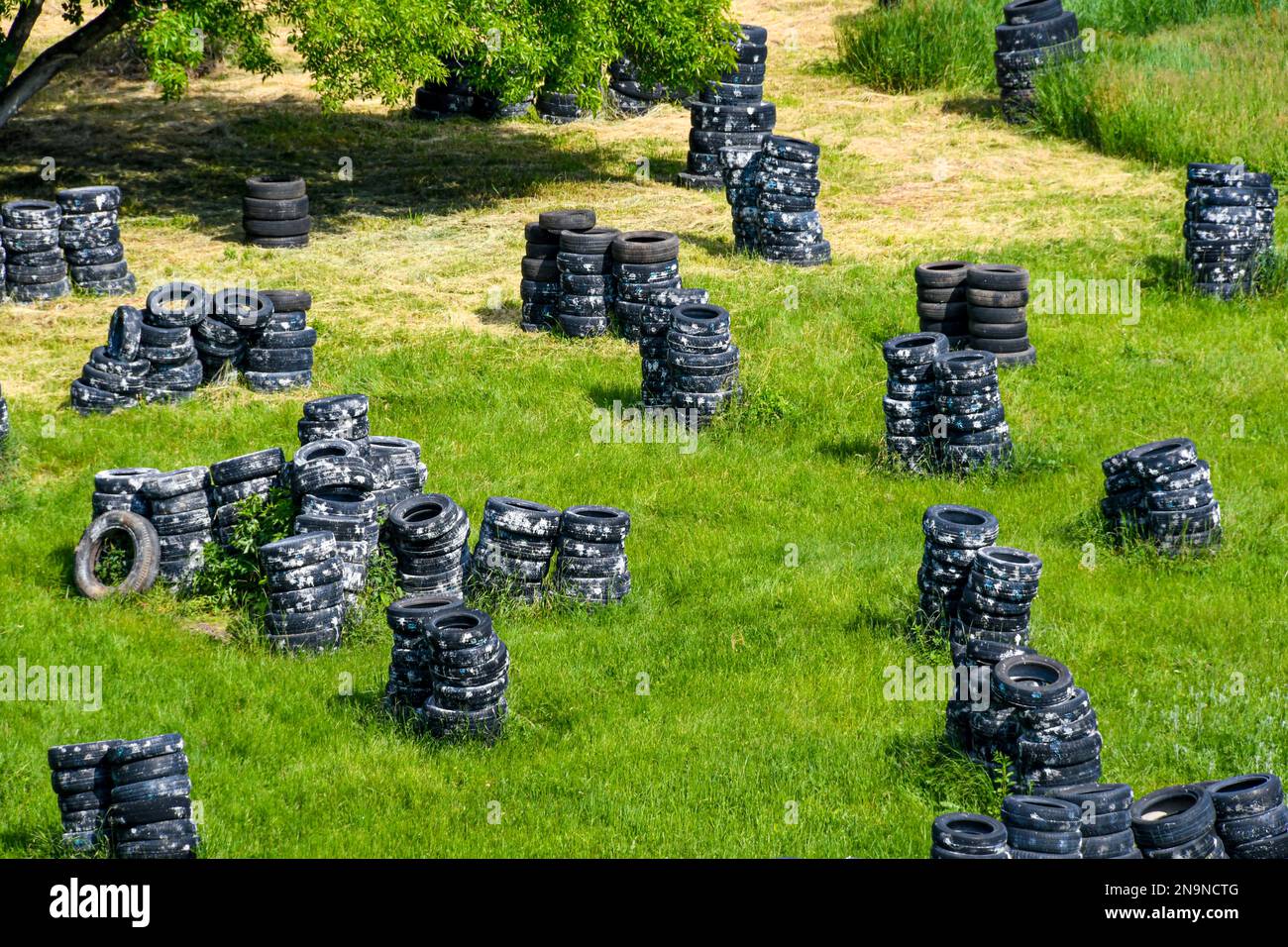 White paint splattered tires on a paintball field in a green field ...
