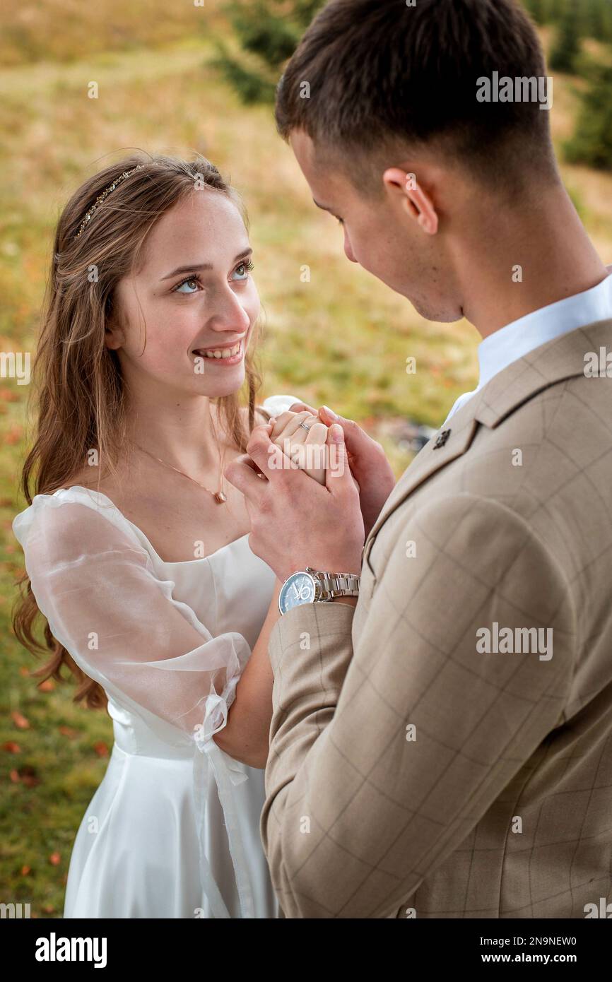 The bride looks at the groom with loving eyes. Smiling newlyweds look ...