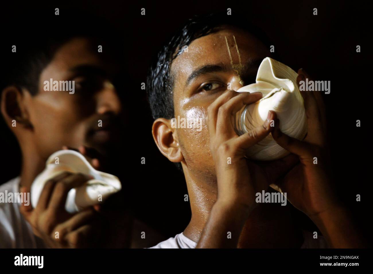 A Hindu devotee blows conch shell during the holy occasion of the ...