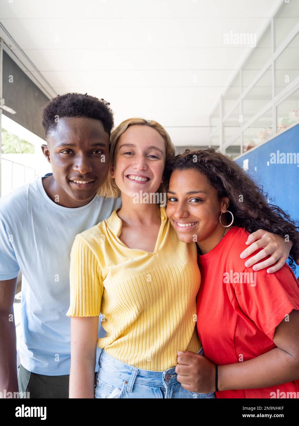 Three multi-ethnic young people laughing and looking at camera having ...