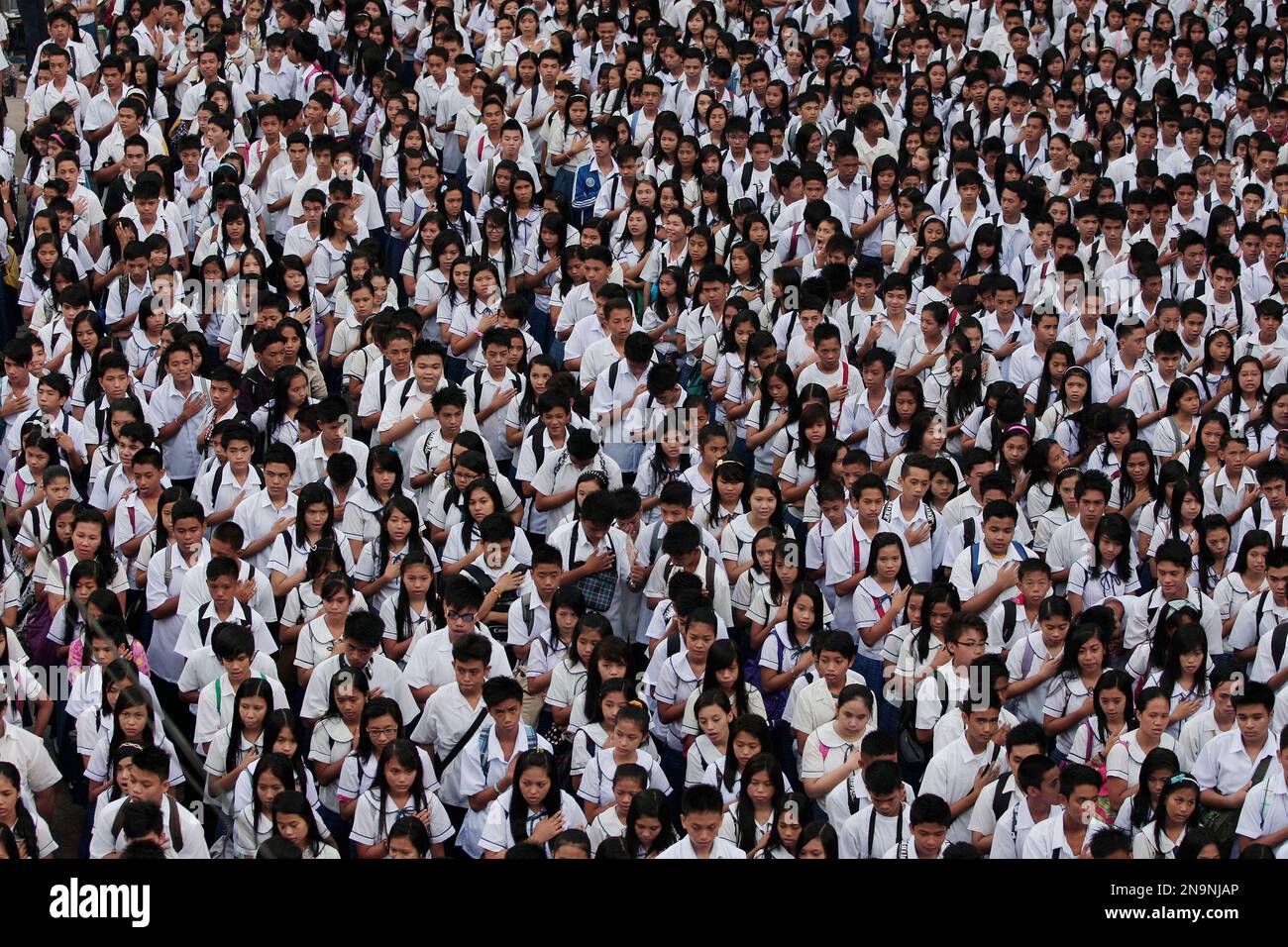 Filipino students place their hands on their chest during flag raising ...