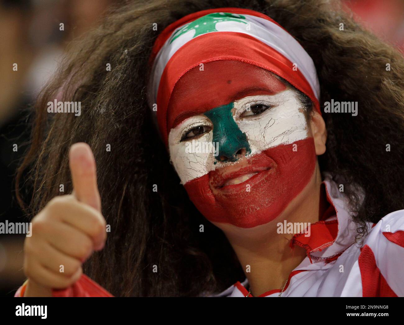 A Lebanese fan, painted her face by the Lebanese flag colors cheers as ...