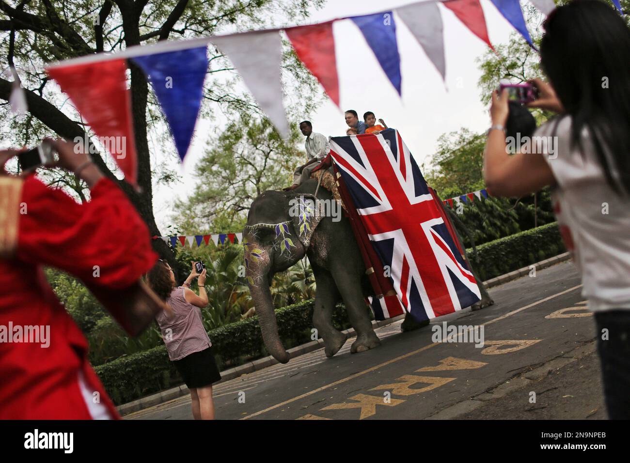 British expatriates ride on Rupa the elephant during a party to ...