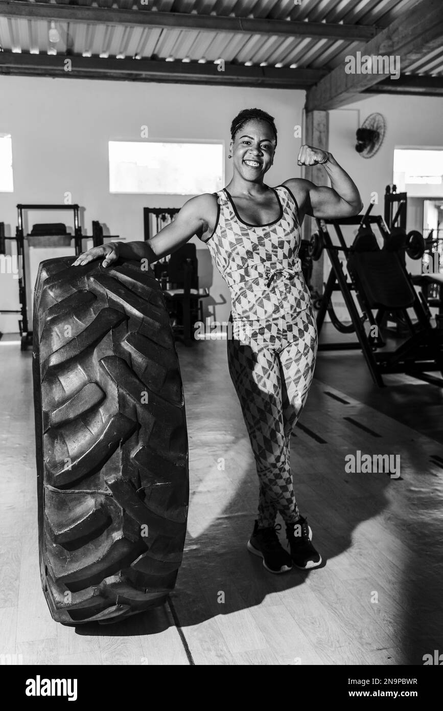 Fitness girl posing next to the tire in the gym. Determination concept ...