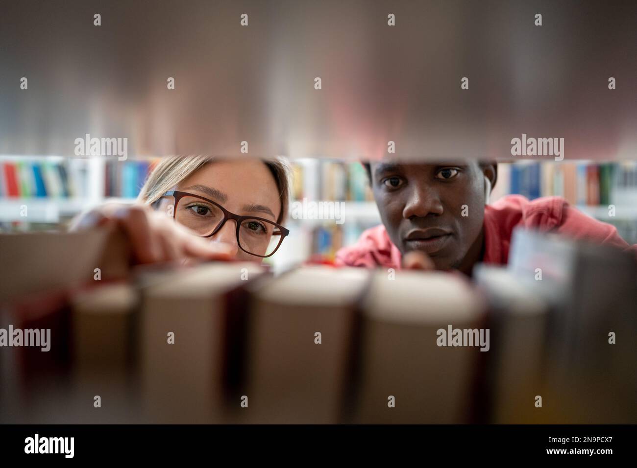 Woman looking through bookshelf hi-res stock photography and images - Alamy