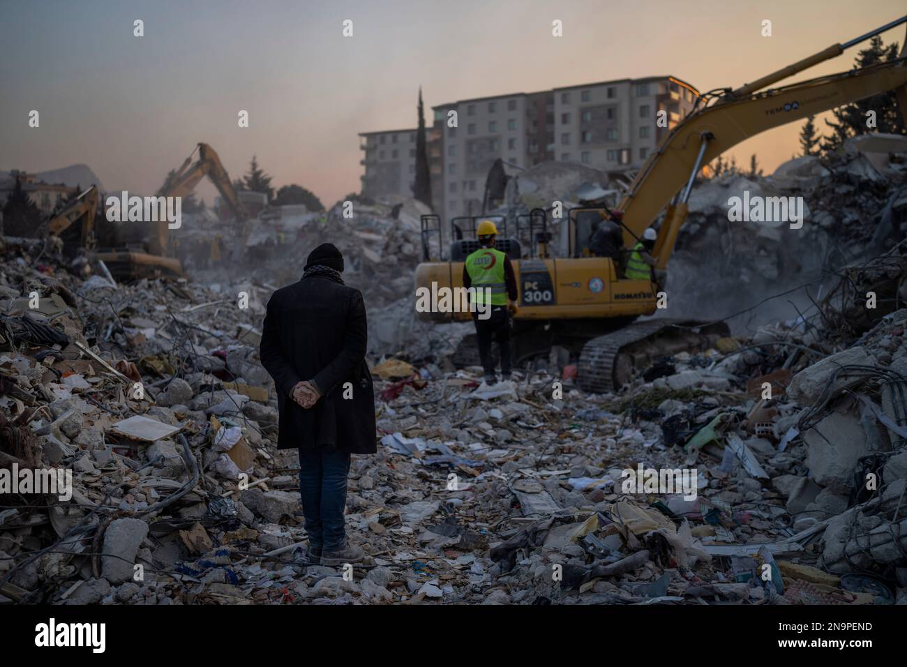 A man stands on top of the rubble of his house destroyed during an ...