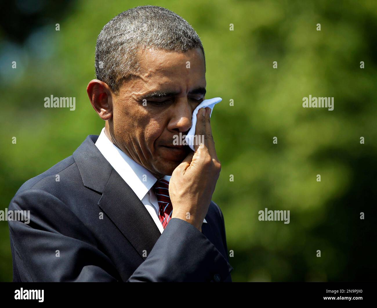President Barack Obama wipes sweat from his face after speaking at the ...