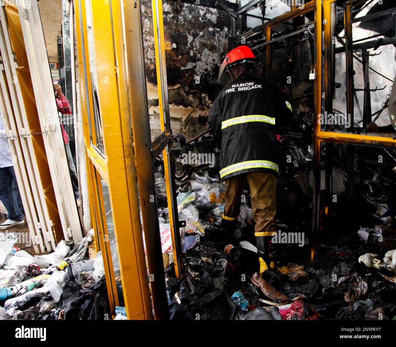 Kenyan firefighter looks through the wreckage of a shop after the ...