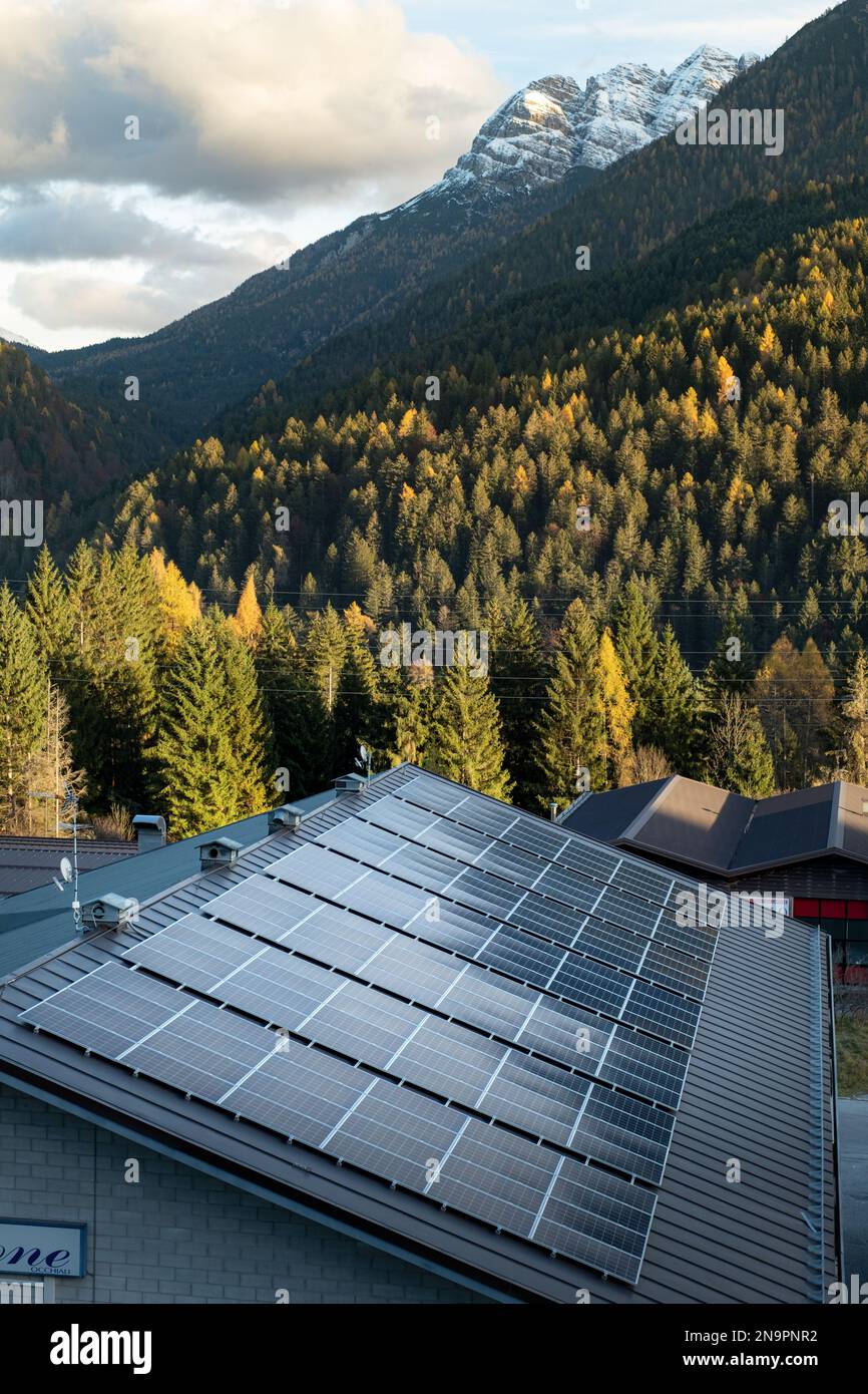 Shiny solar energy panels on house roofs near cascading green mountains ...