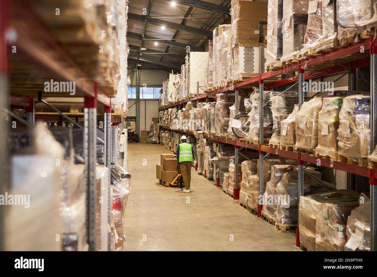 Wide angle view at storage warehouse interior with worker pushing cart ...