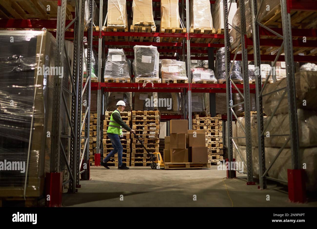 Side view view at storage warehouse interior with worker pushing cart ...