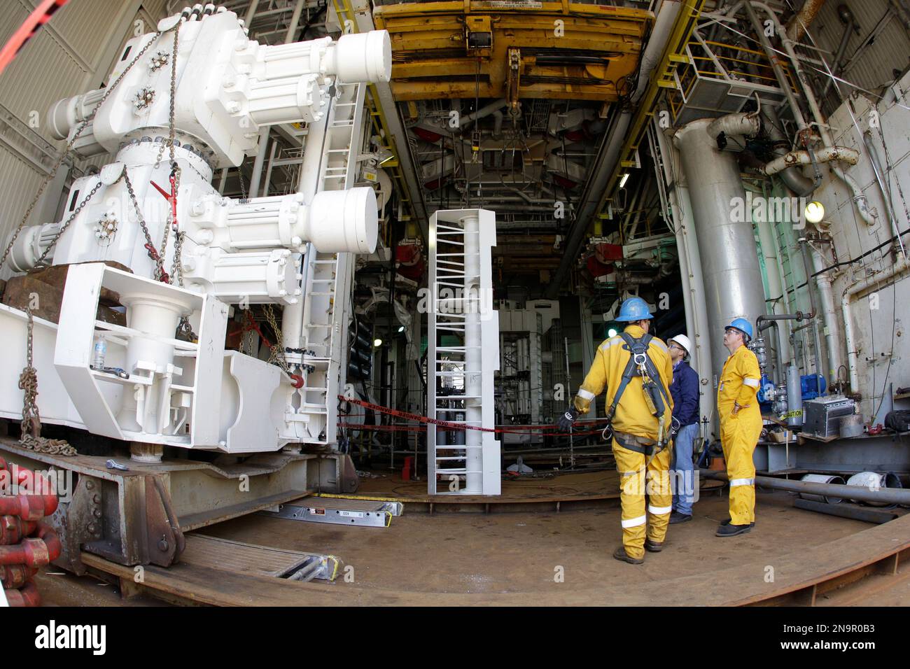 Workers stand next to one of two giant blowout preventers on board the ...