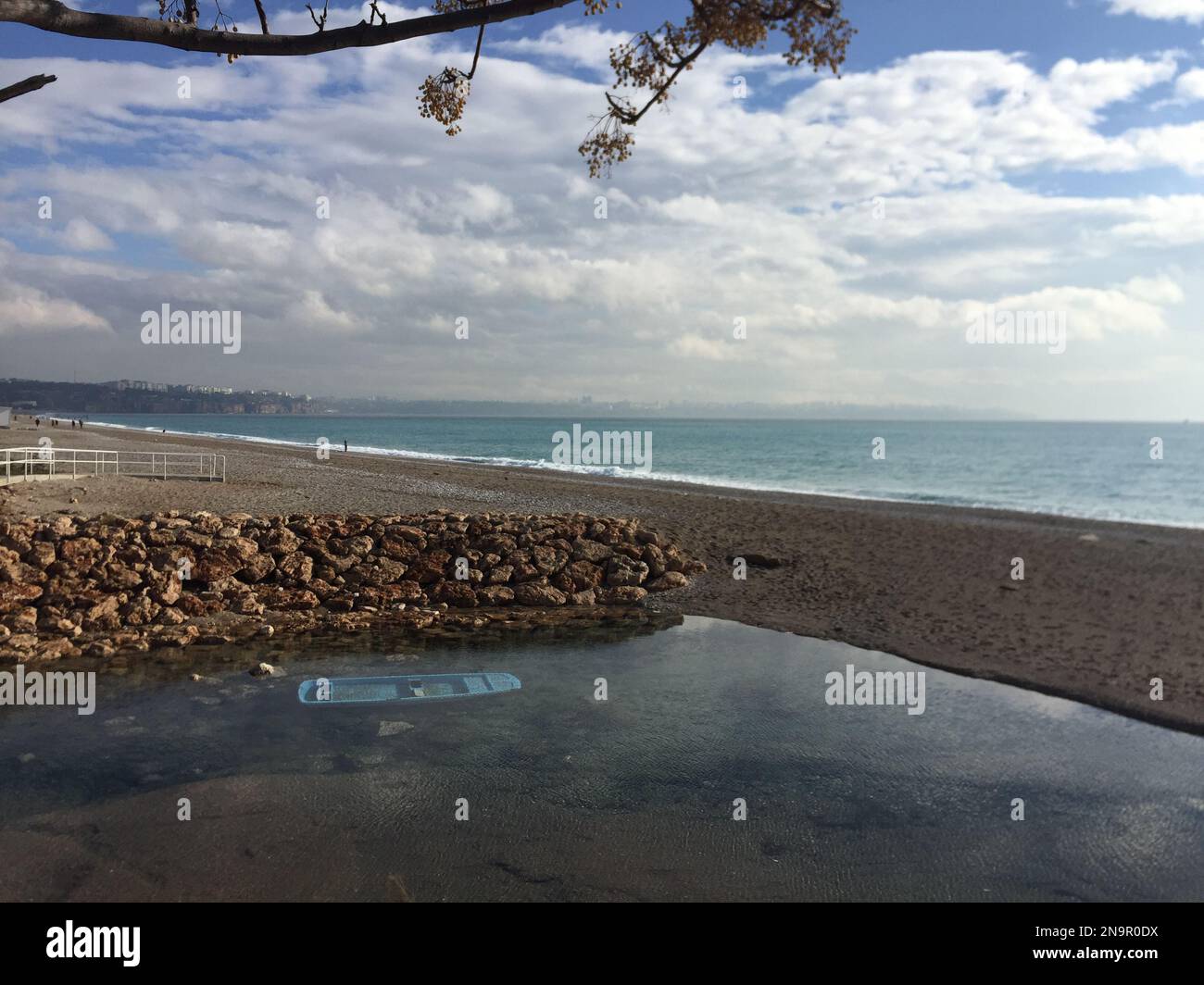 A blue sunken boat in a puddle by the sea. White clouds, clear seaside ...