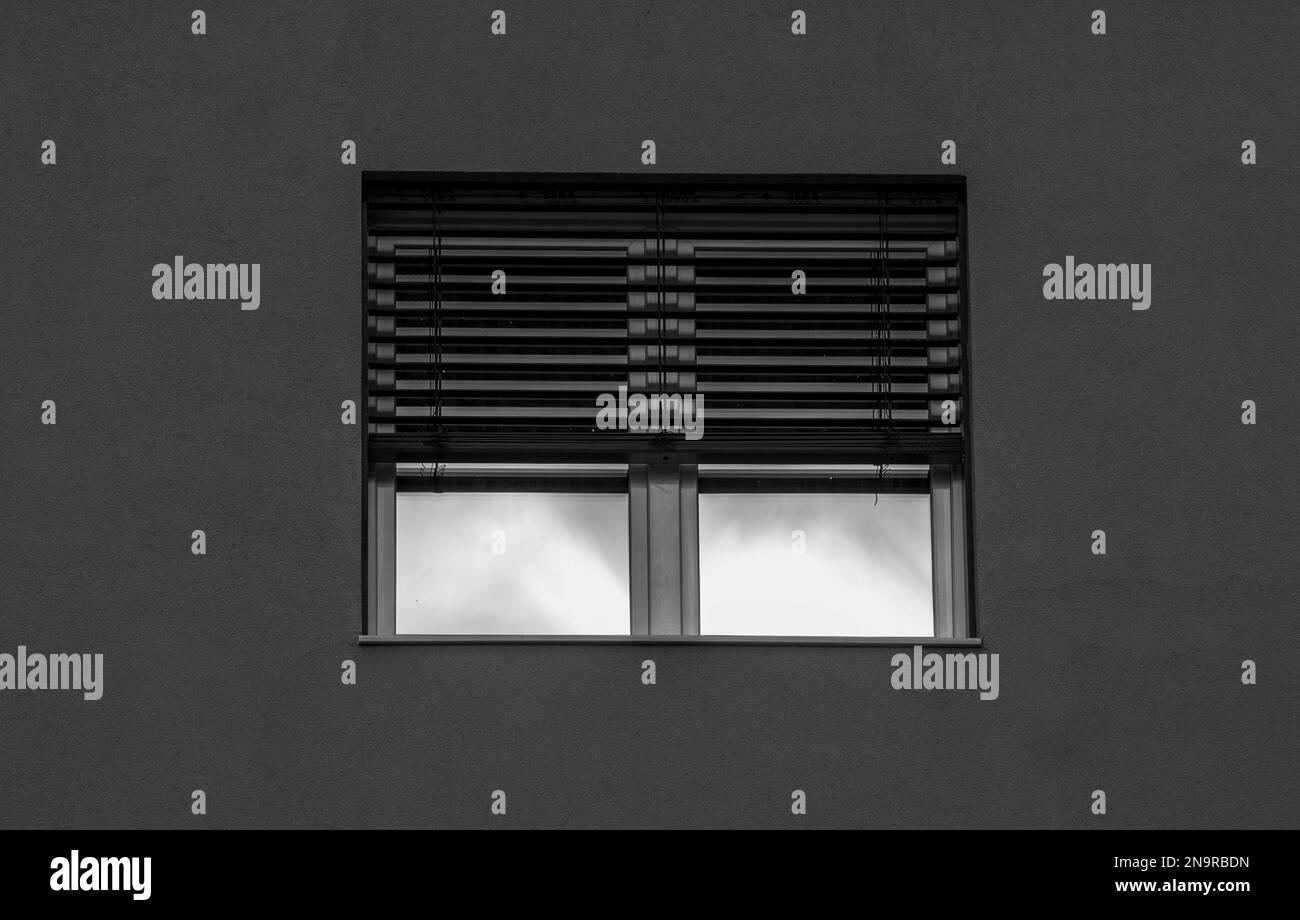 A grayscale of a window with a frame on the gray wall with the daytime ...