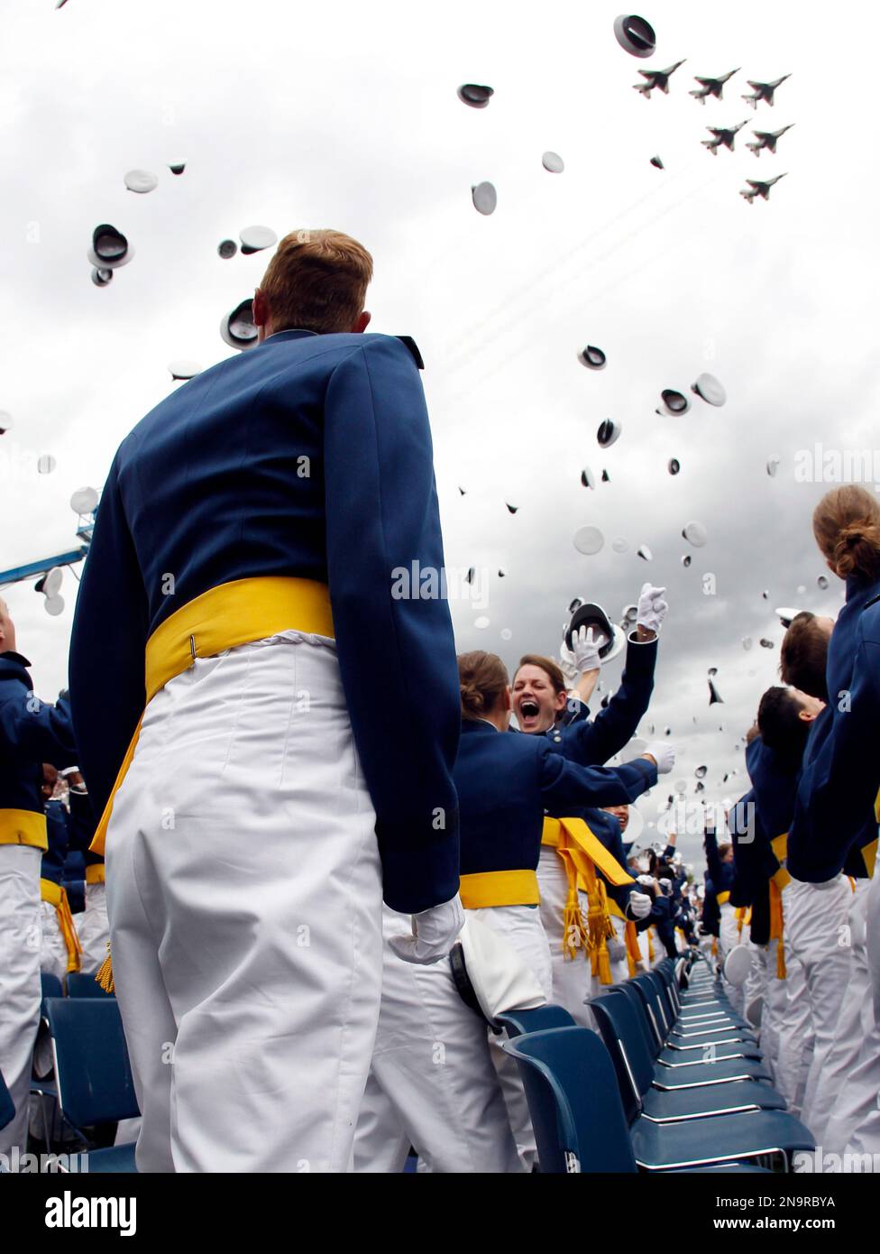 Jets fly over as cadets throw their hats in the air after the ...