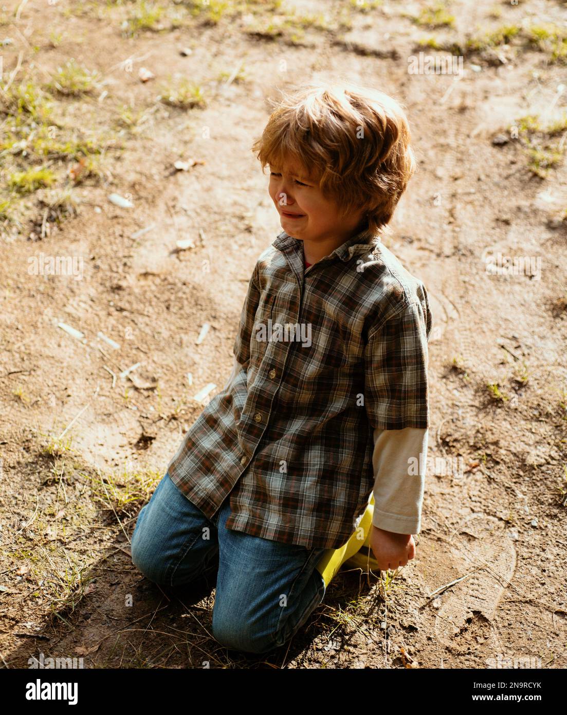 A toddler is falling down on the road. Kids emotional concept. Blonde ...