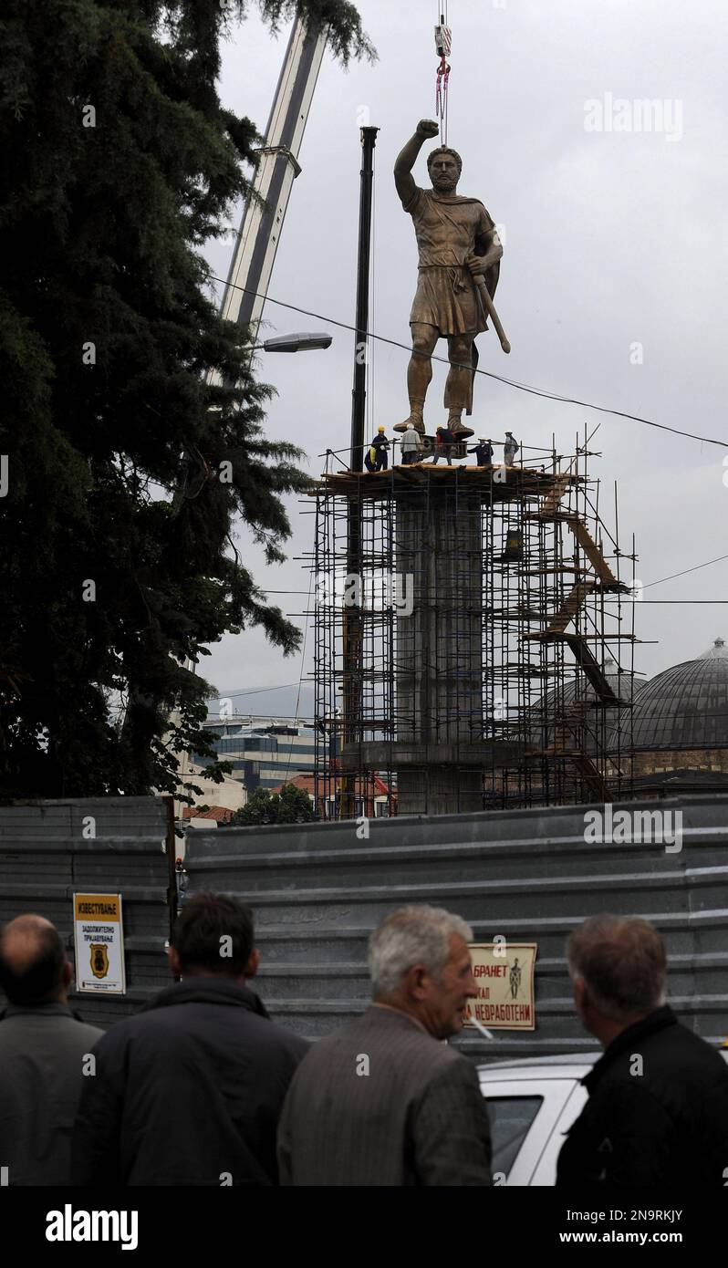 People look as workers place a 13-meter-high bronze statue named as ...