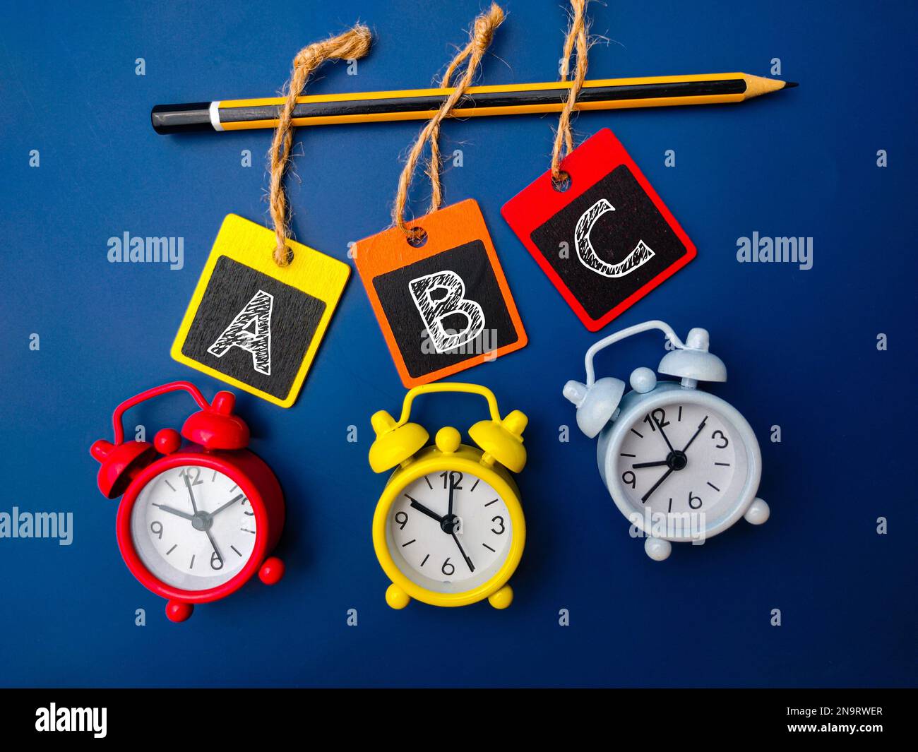 A Top view of red, blue and yellow alarm clocks with the letters A B C ...