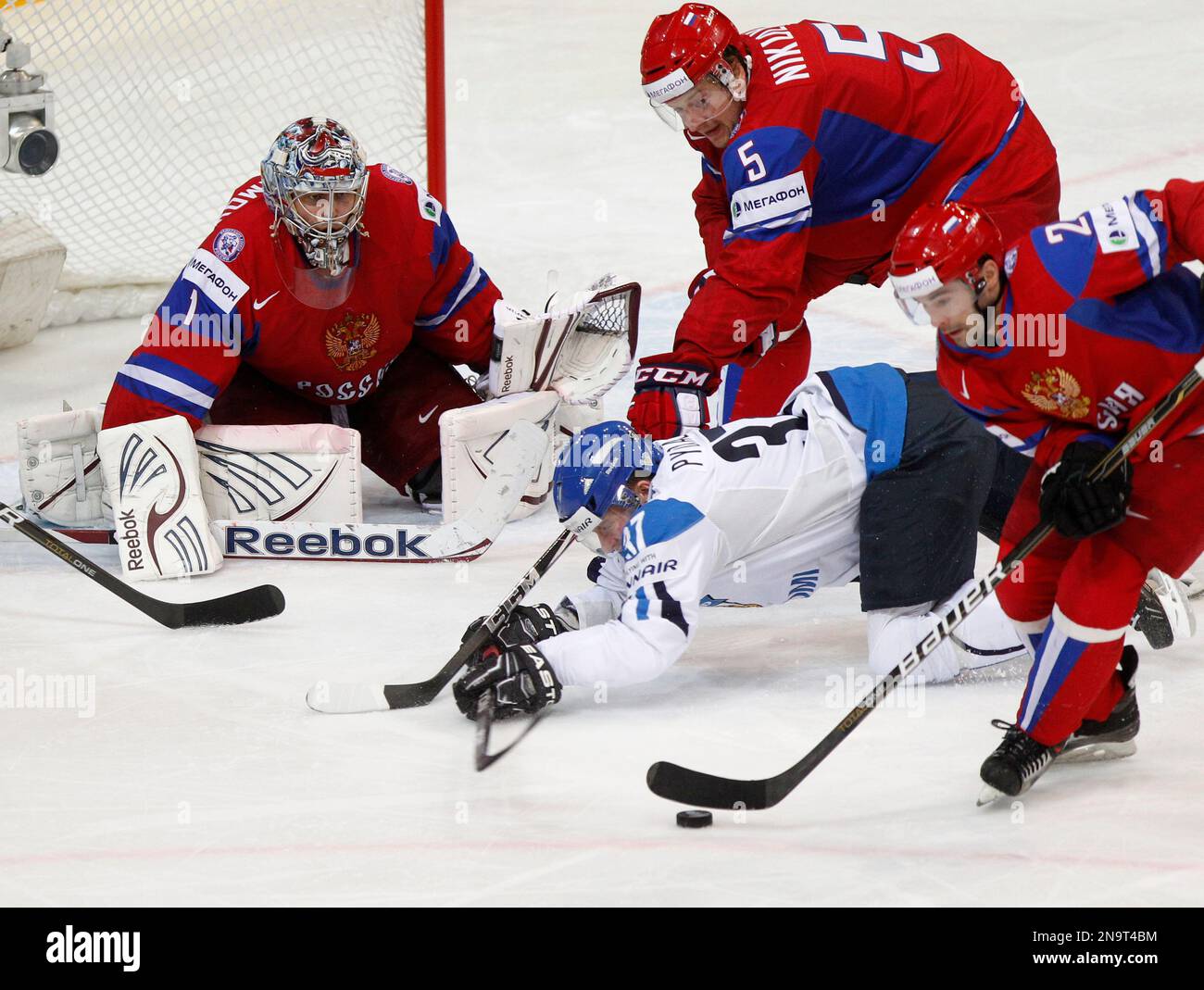 Finland's Mika Pyorala, center, fights for the puck with Russia's Ilya Nikulin, above and ...
