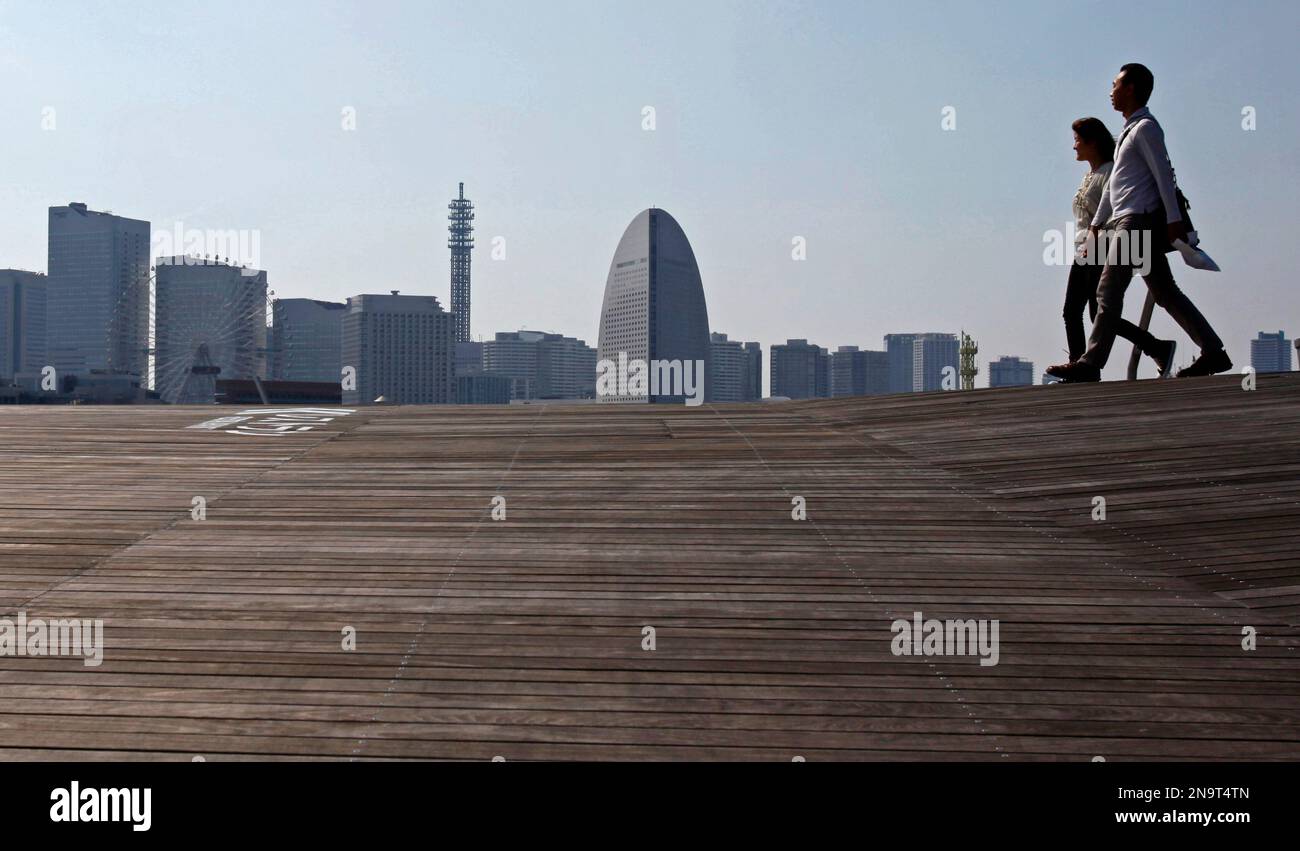 Visitors walk on the wood deck of a waterfront park in Yokohama, Japan ...