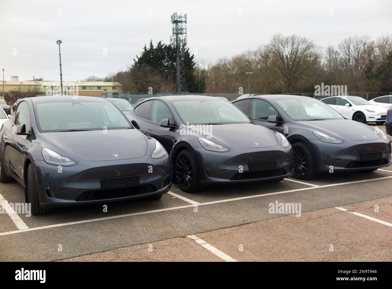 Tesla Electric vehicle EV cars waiting at a delivery collection car hub ...